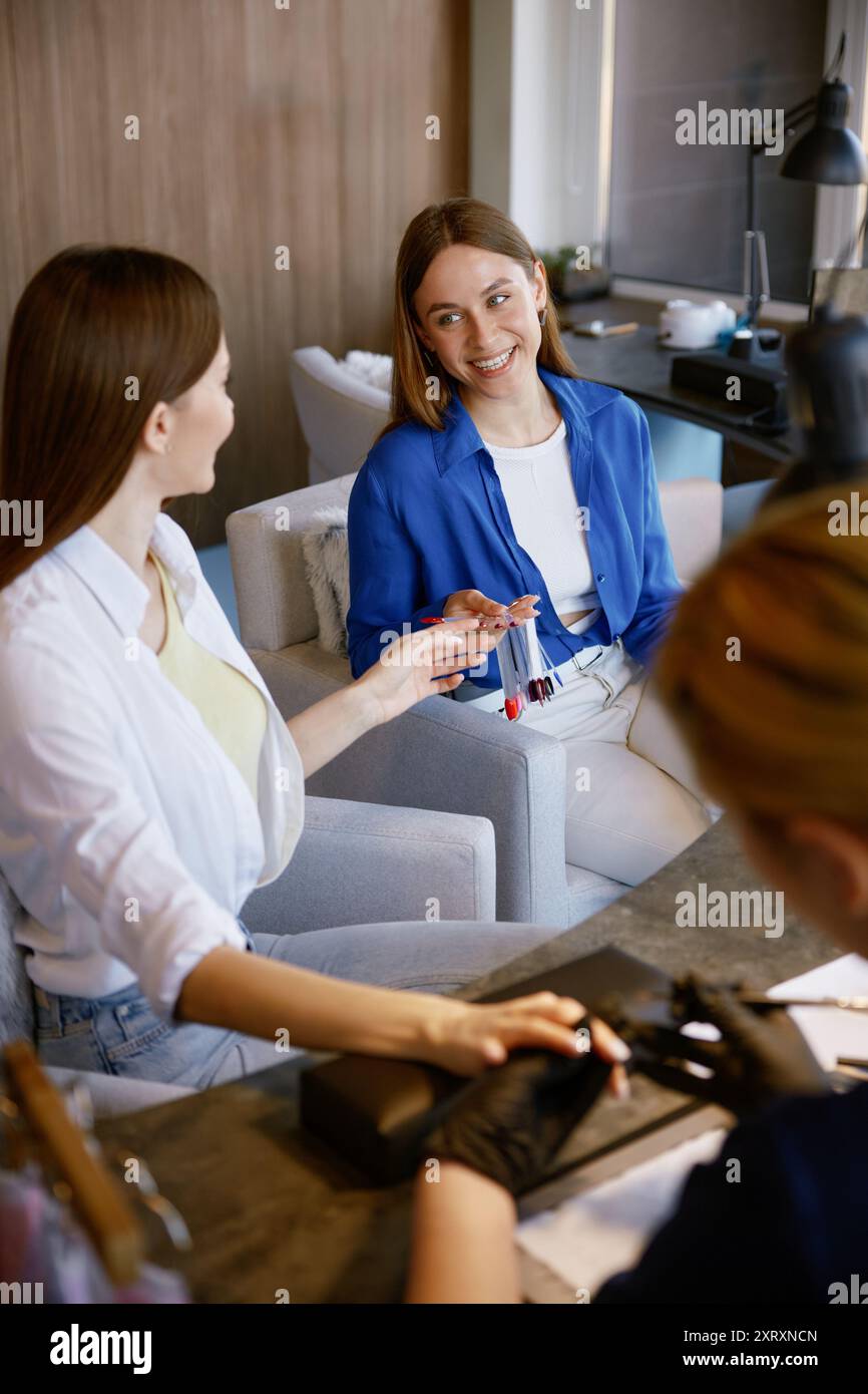 Young woman advising friend color of nail polish in spa salon Stock ...
