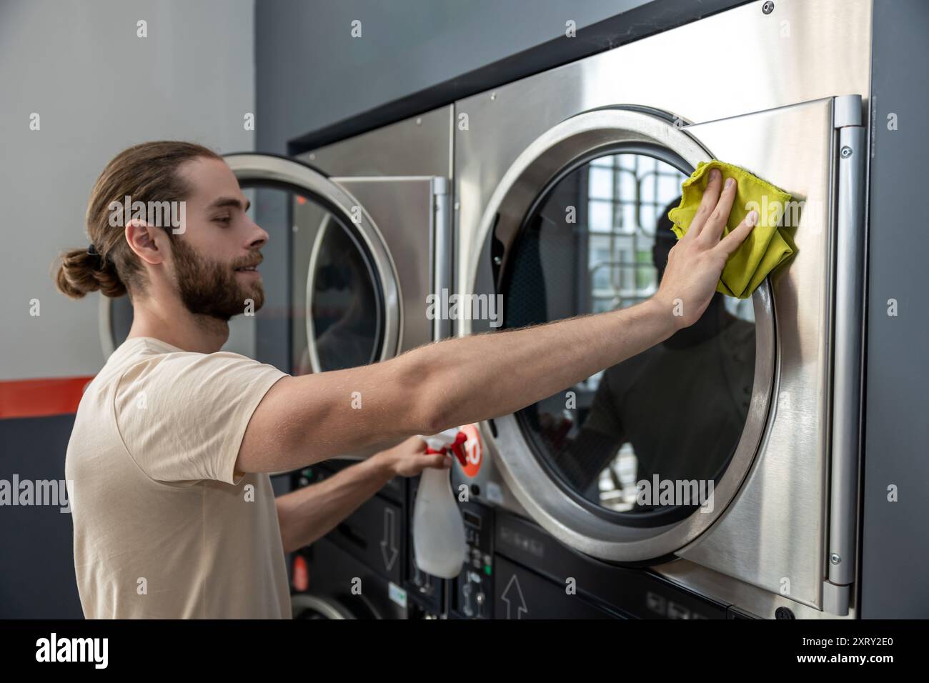 Bearded man washing machine with detergent in self-service laundry ...