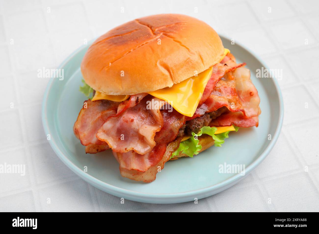 Delicious burger with bacon, patty and cheese on white tiled table ...