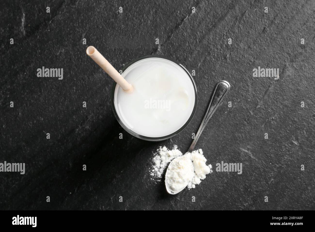 Delicious protein shake in glass and spoon with powder on black table ...
