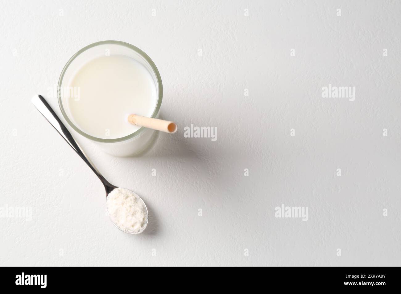 Delicious protein shake in glass and spoon with powder on white ...