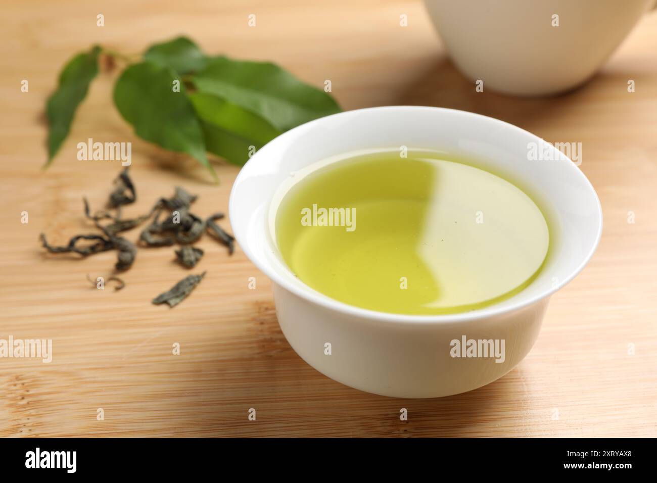 Refreshing green tea in cup and leaves on wooden table, closeup Stock ...
