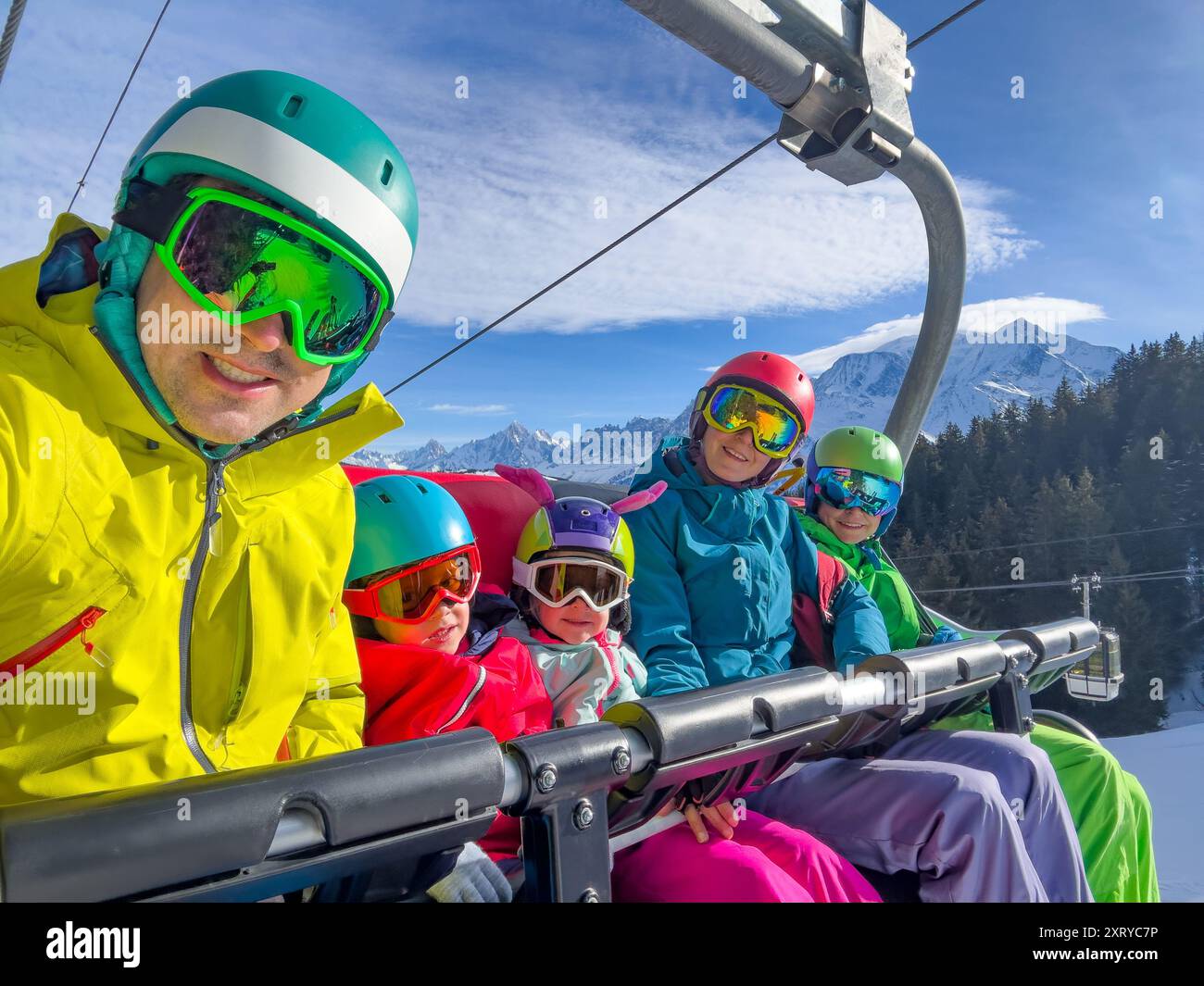 Fun family ski trip, captured on lift, snowy mountains around Stock ...