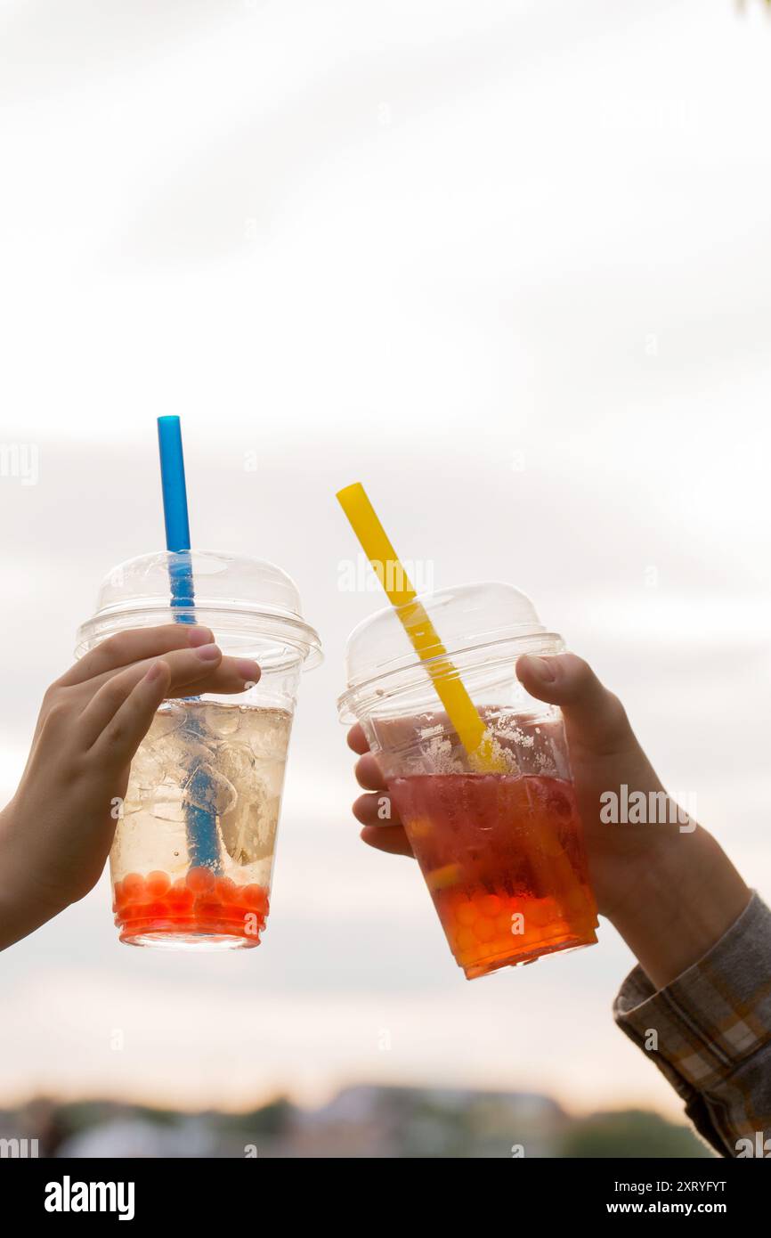 Two children drink bubble tea from plastic cups on a walk in the ...