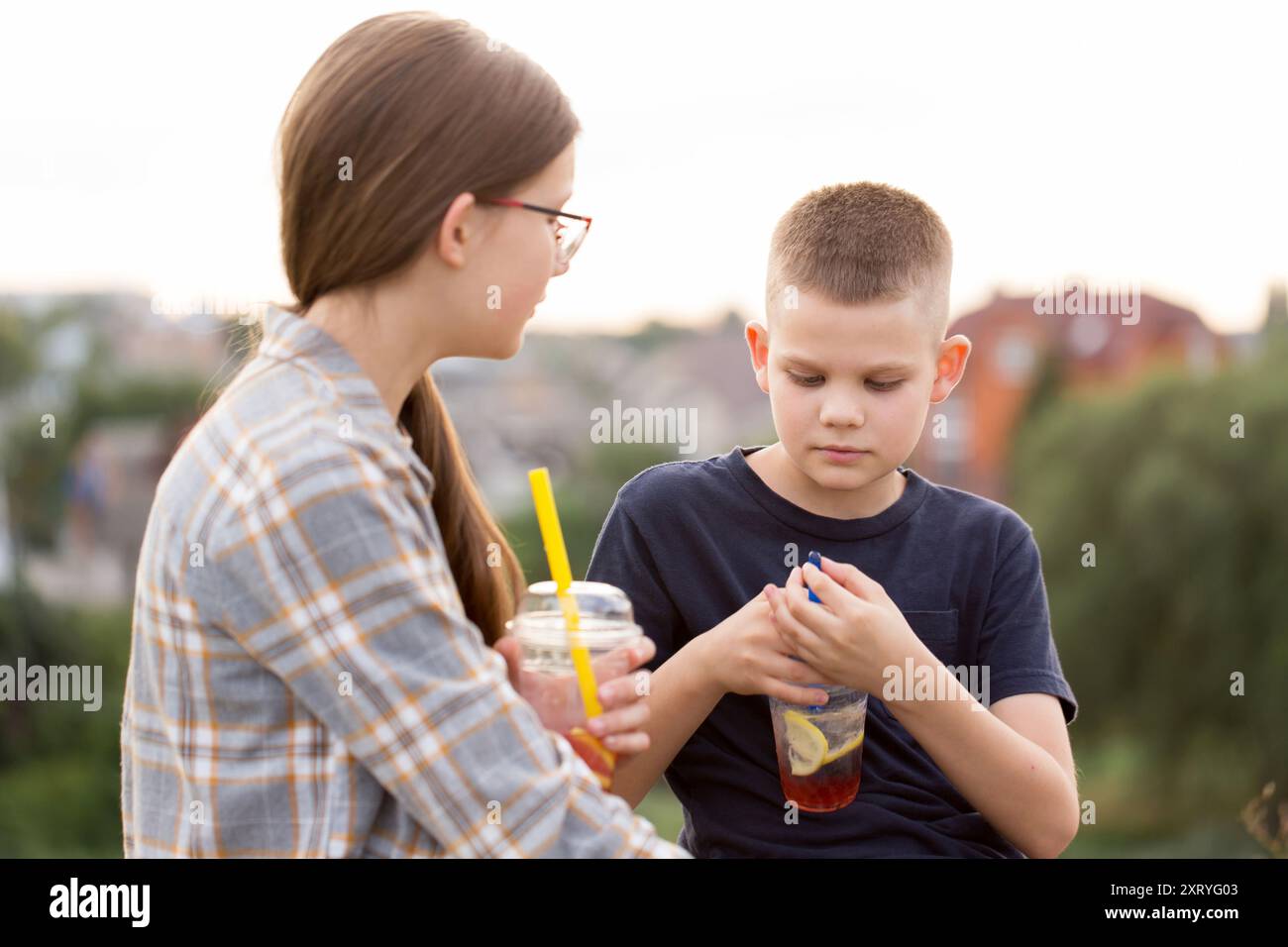 Two children drink bubble tea from plastic cups on a walk in the ...