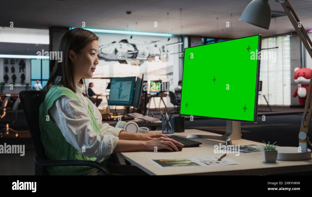 Female Asian Game Programmer Coding On Desktop Computer With Green