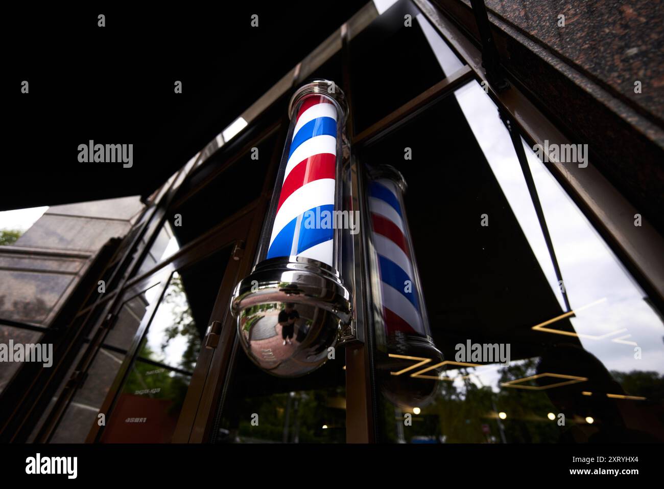 Barber pole outside a traditional barber shop in the city reflecting ...