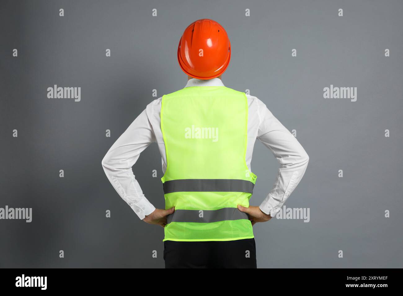 Engineer in hard hat on grey background, back view Stock Photo - Alamy