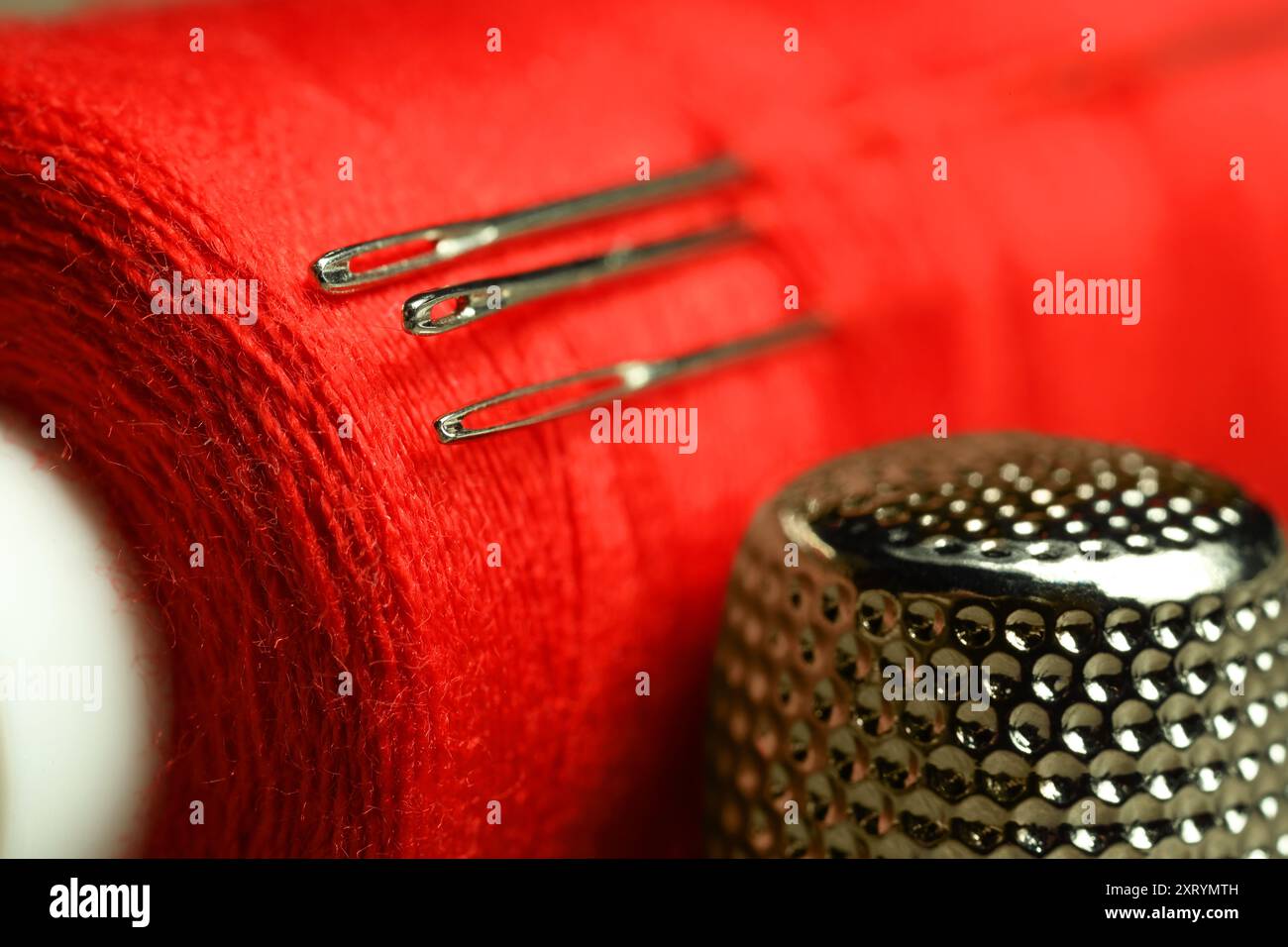 Spool of red sewing thread with needles and thimble, closeup Stock ...