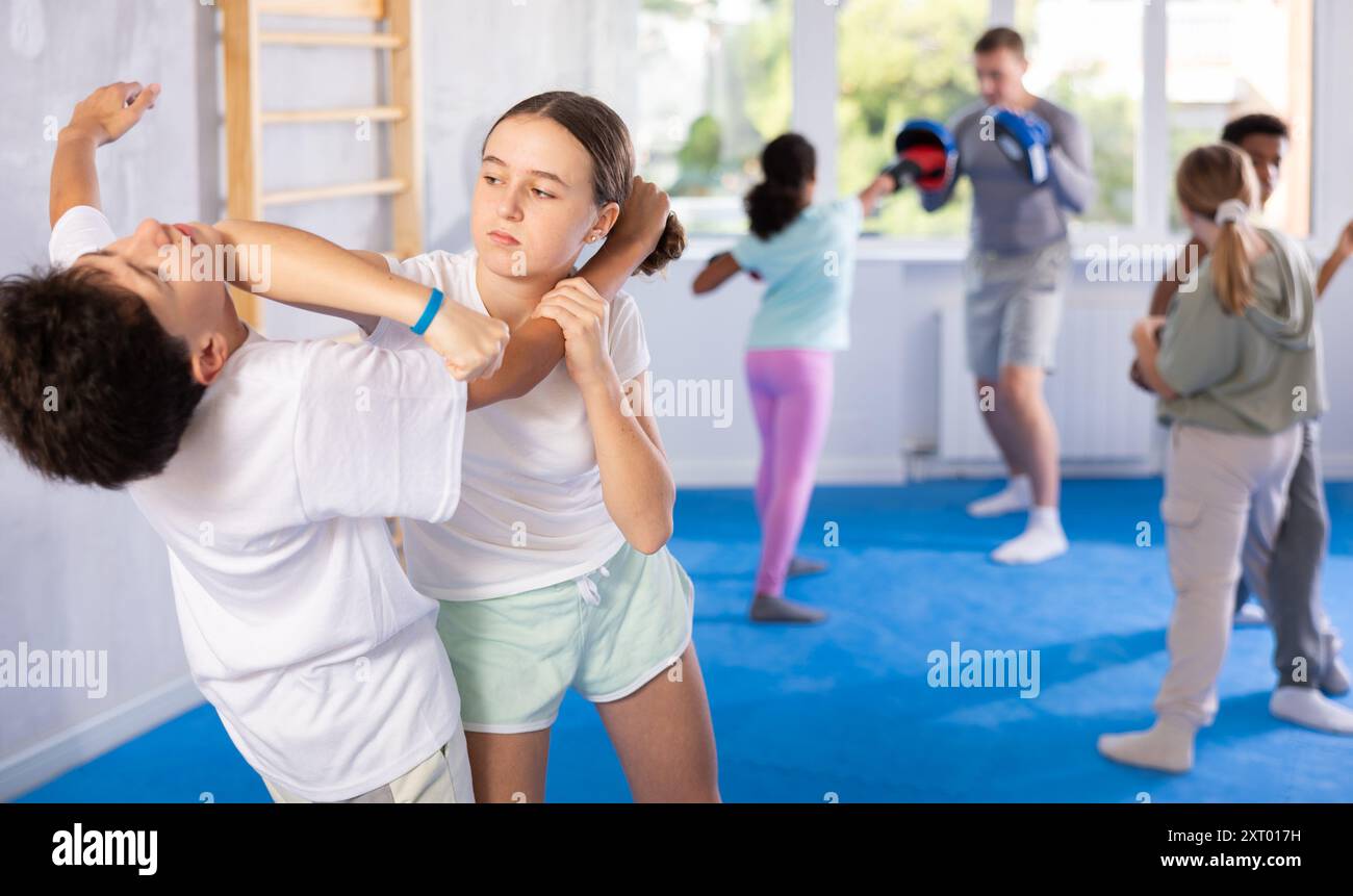 Girl practicing armlock with elbow strike to chin in mock bout with boy ...