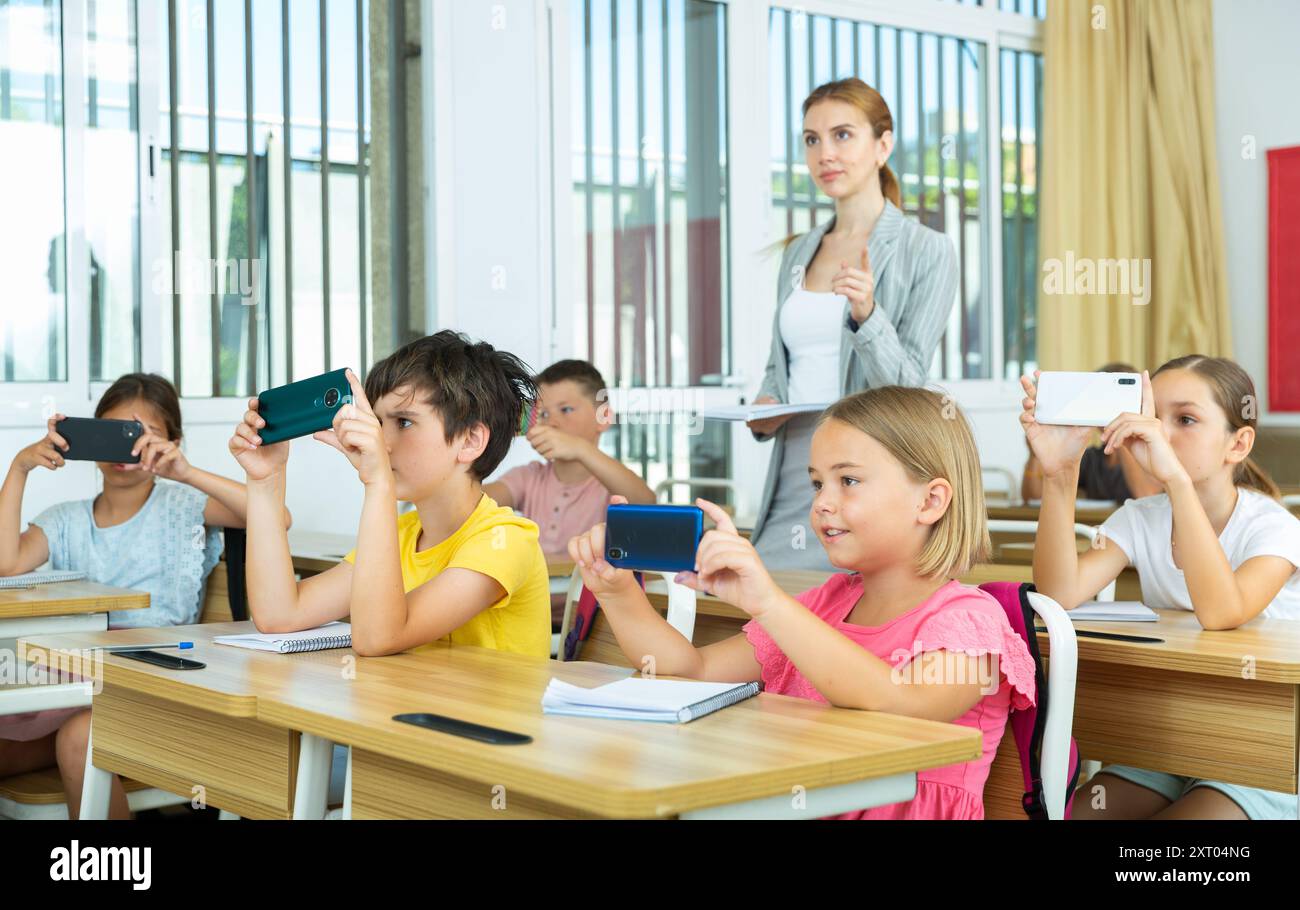 Absorbed preteen school children using mobile phones at lesson Stock ...