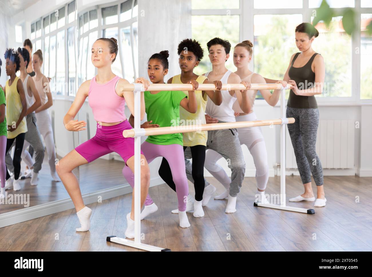 Woman teacher corrects teenagers in plie movement Stock Photo - Alamy