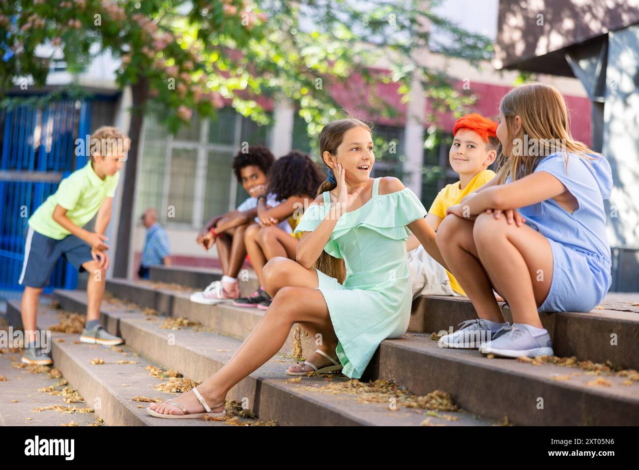 Group of kids sitting on stairs outdoors and talking Stock Photo - Alamy