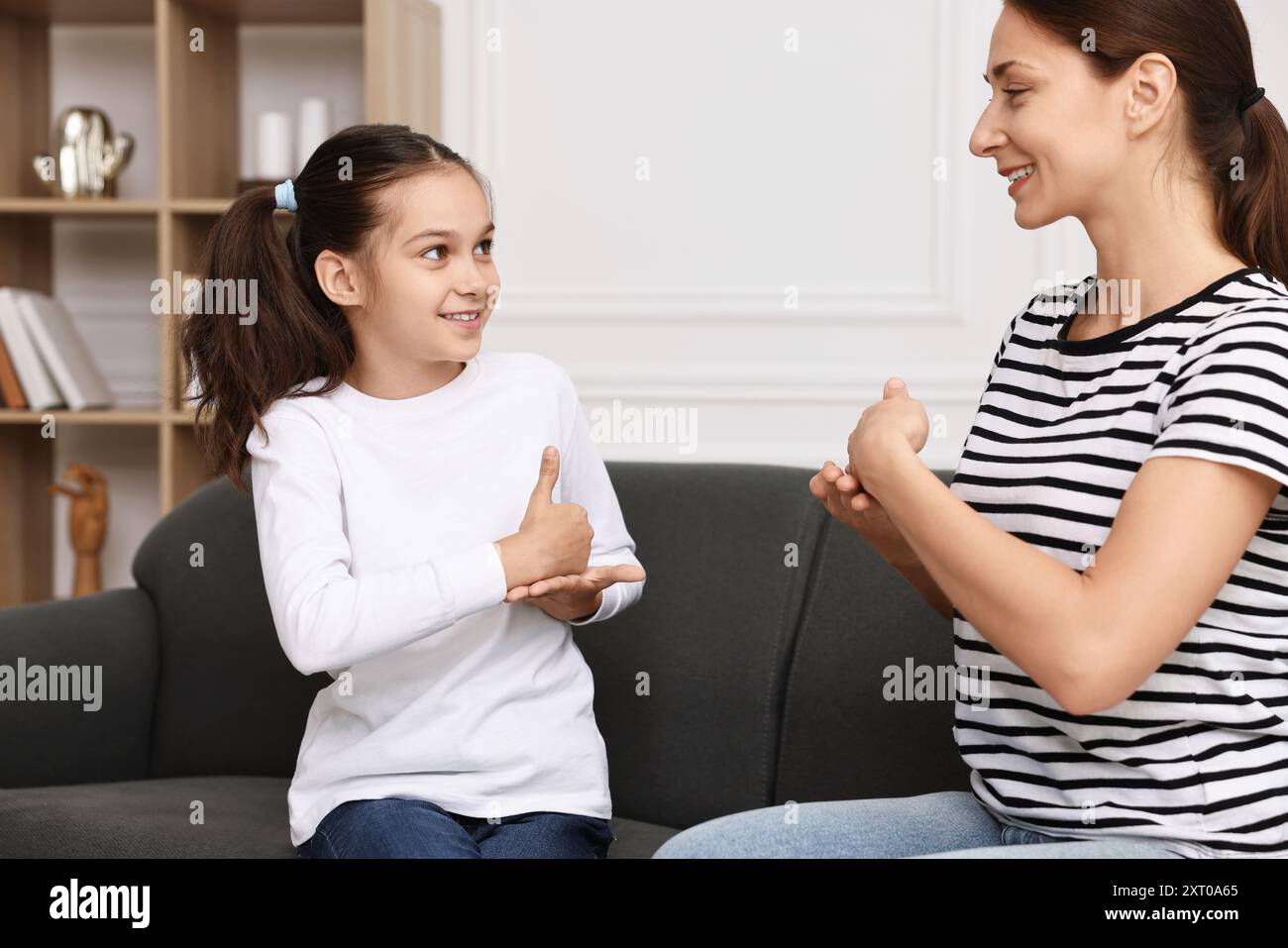 Woman and her daughter using sign language for communication at home ...