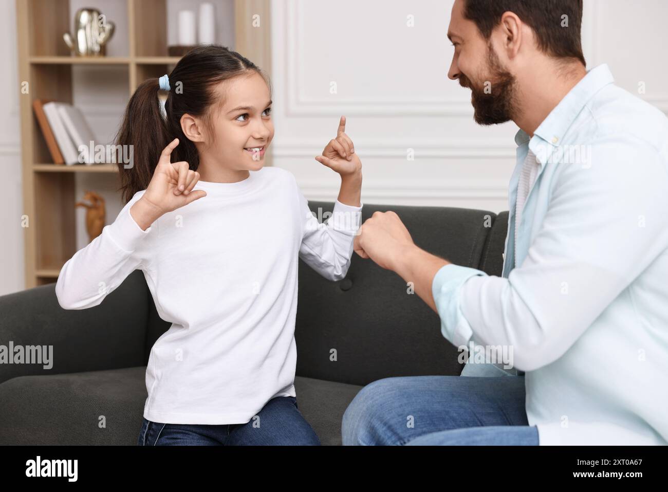 Man and his daughter using sign language for communication at home ...