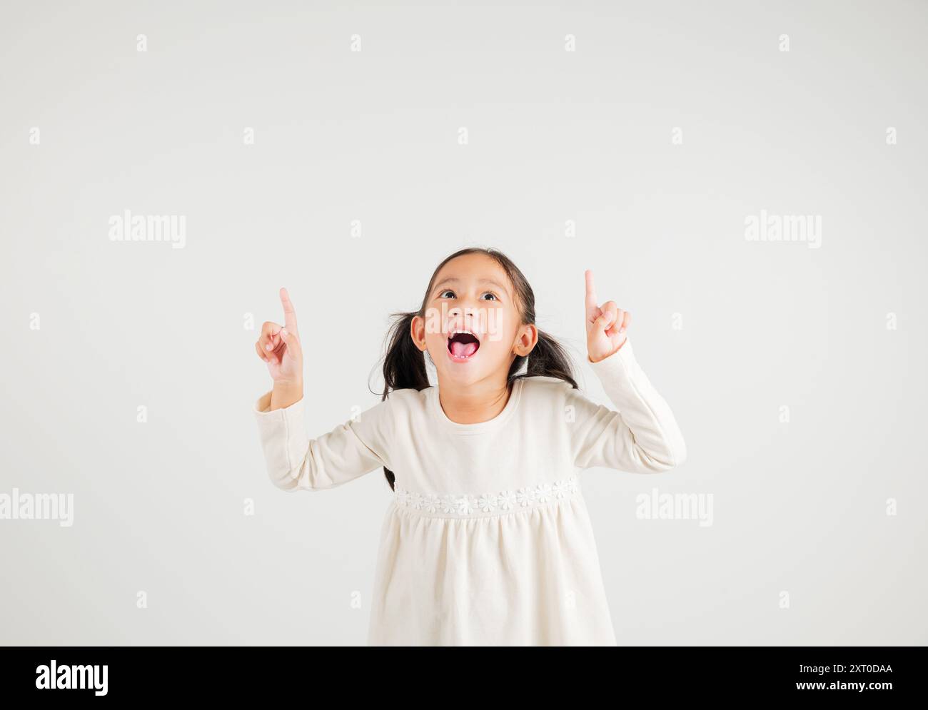 Asian happy portrait cute young kid girl makes gesture fingers point ...