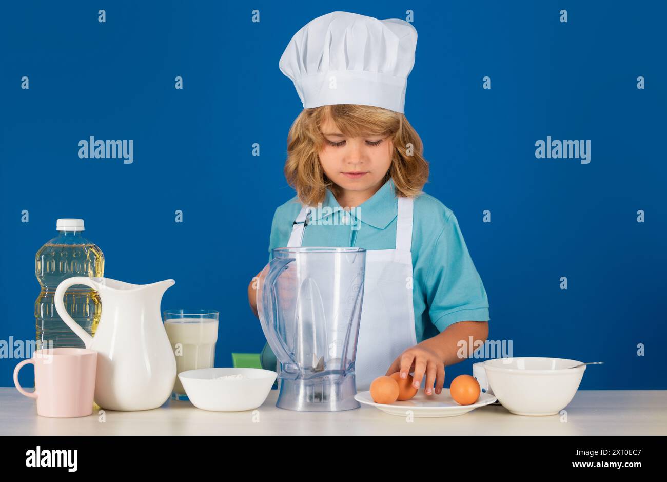 Kid boy in chef hat and apron cooking preparing meal. Little cook with ...