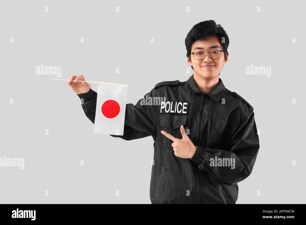 Young Asian police officer pointing at flag of Japan on light ...