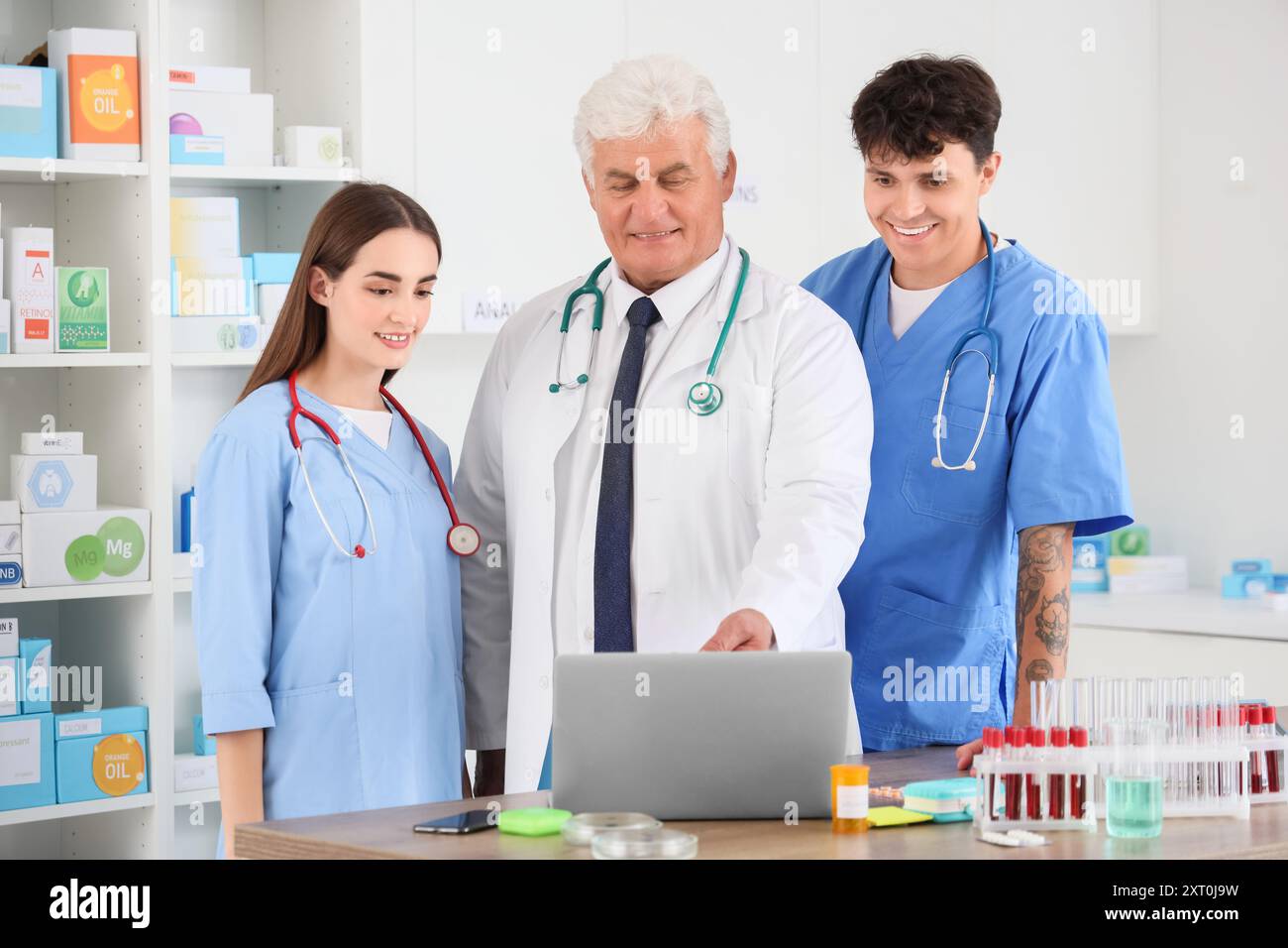 Mature doctor with medical students studying with laptop at university ...