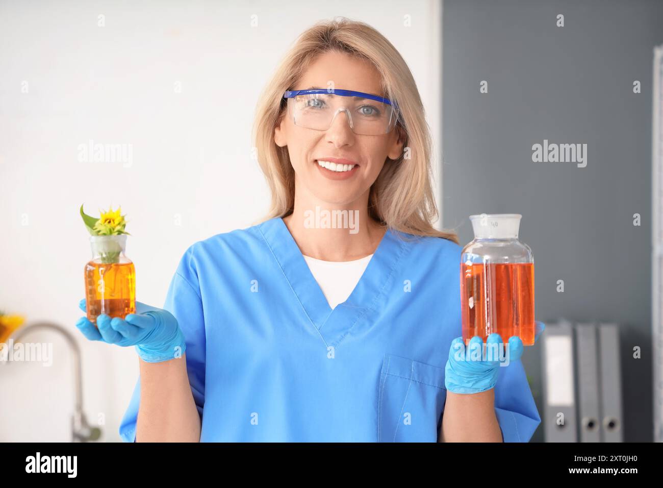Happy female scientist with flasks of samples and sunflower in ...