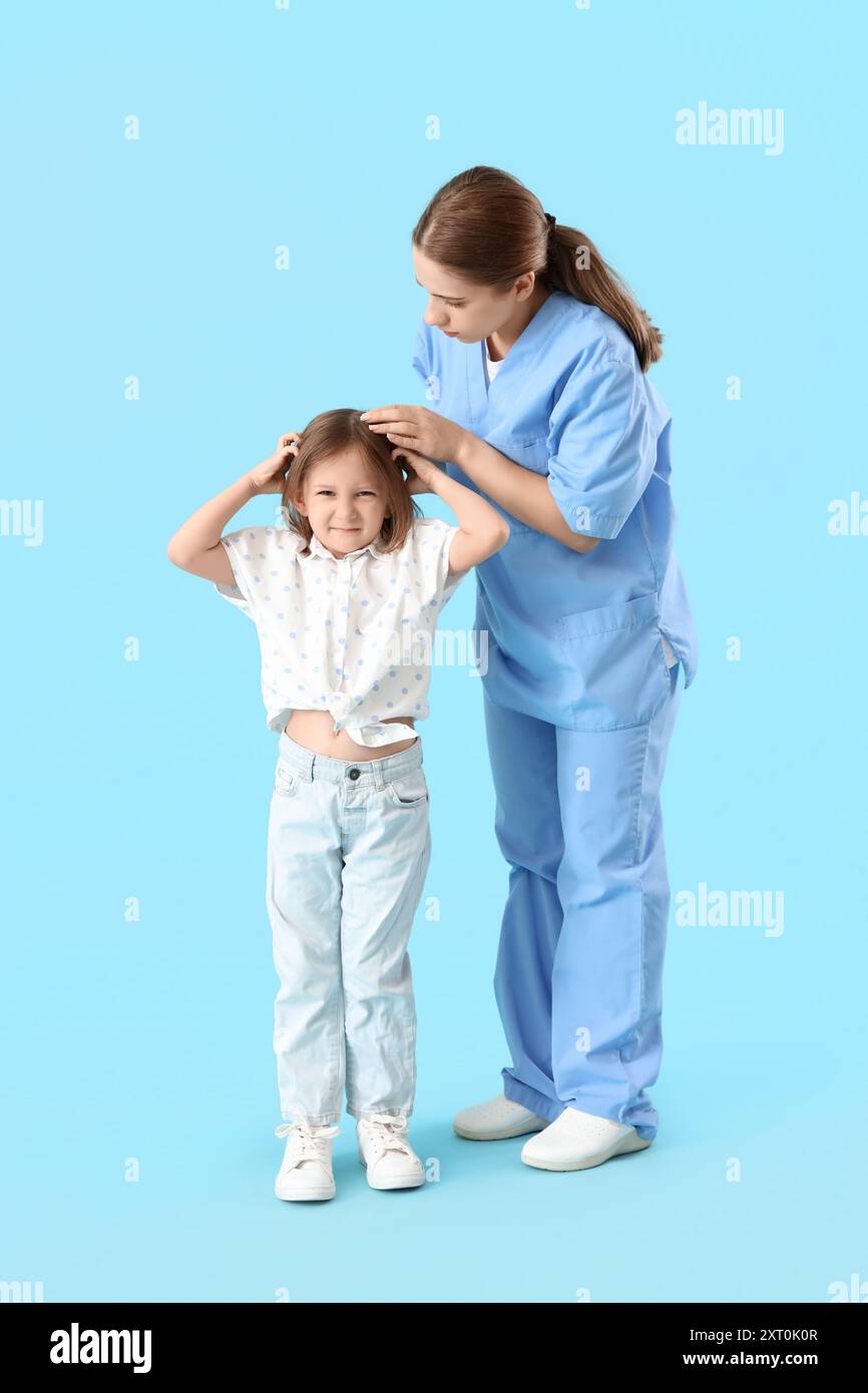 Female doctor checking little girl's head with pediculosis on blue ...