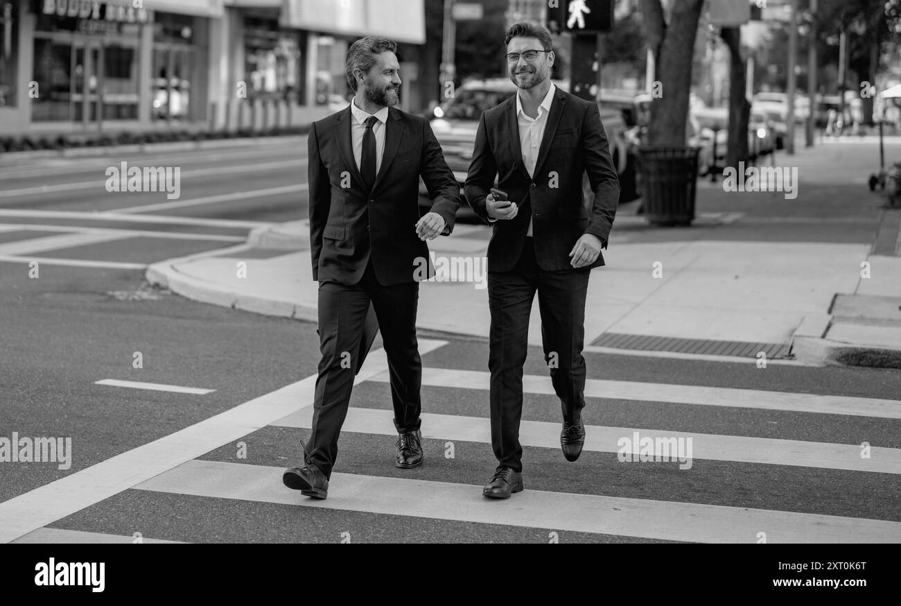 Businessmen walk in the street. Two businessmen walking and talking at ...