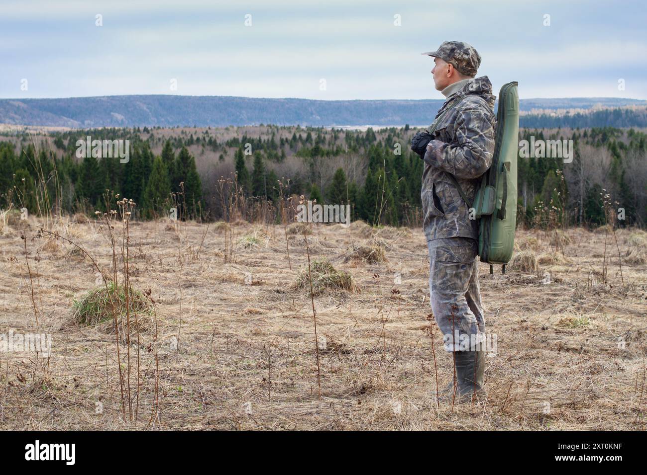 A shotgun case is slung over the shoulder of a hunter standing in a ...