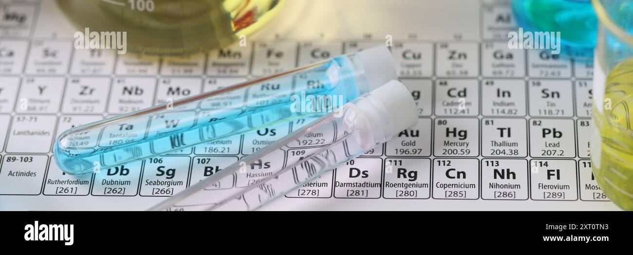 Research laboratory glassware with liquids on periodic table of ...