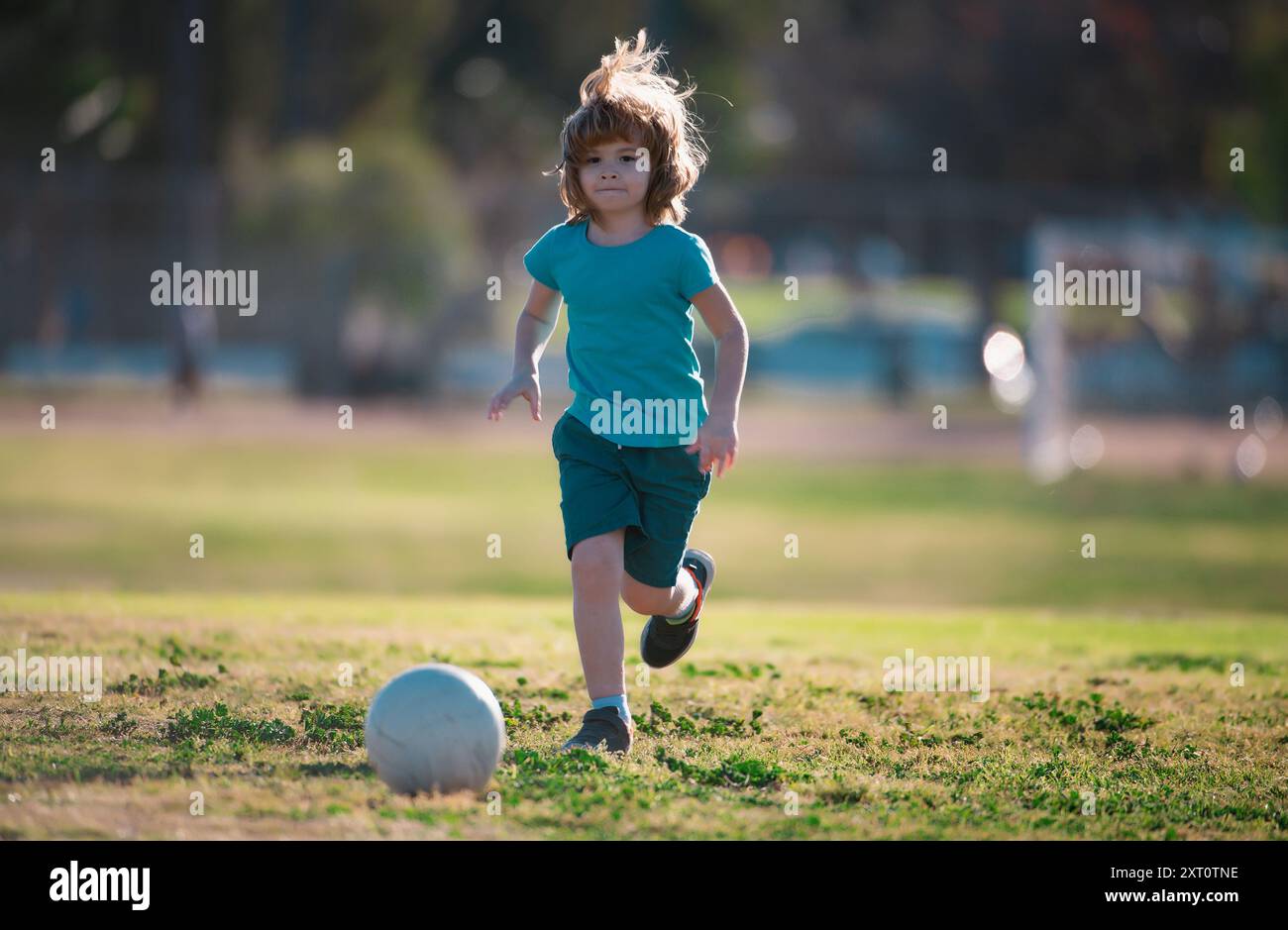 Boy child playing football on football field. Kid playing soccer ...