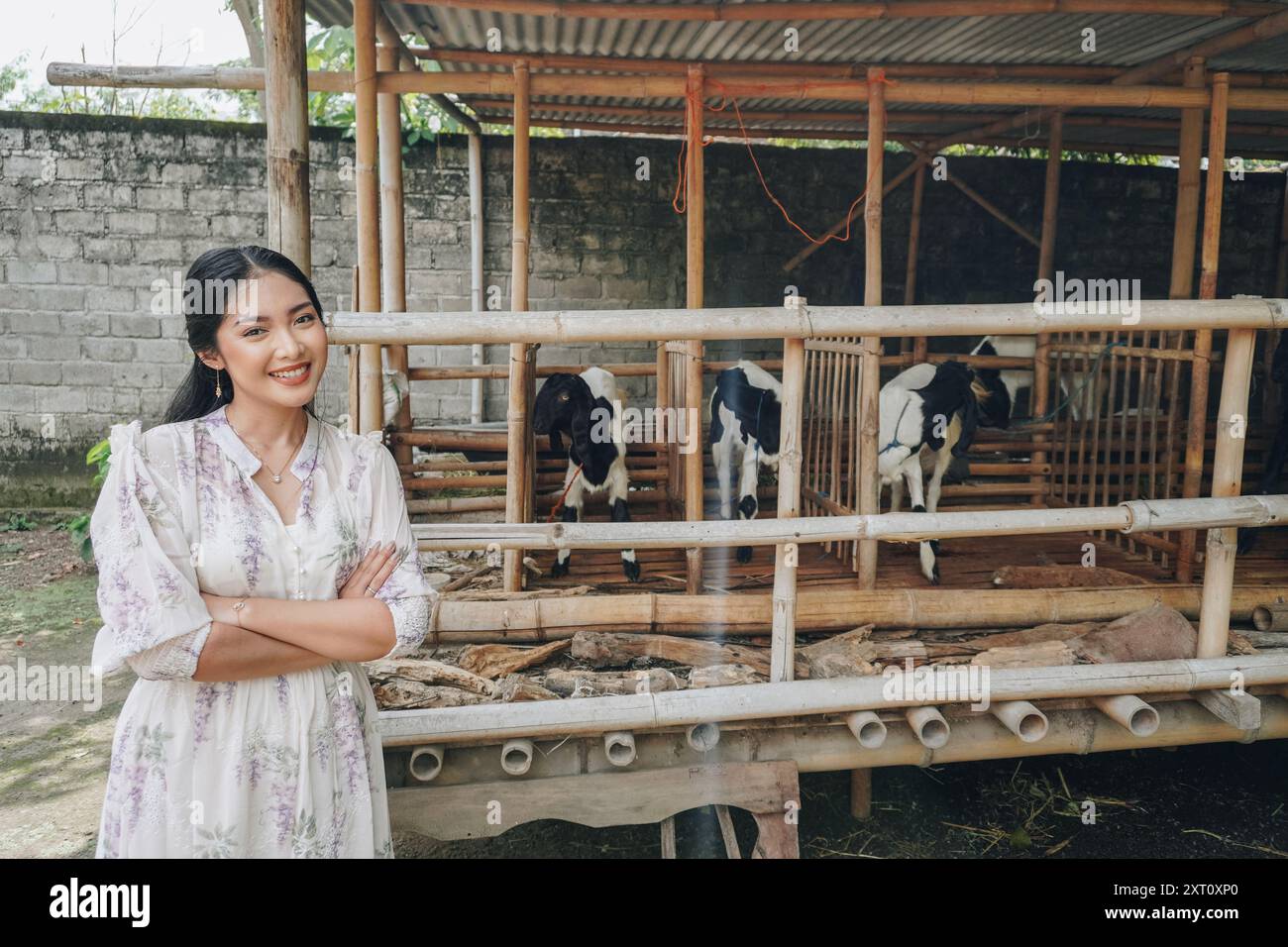 Smiling young Asian woman standing in front of traditional cage made ...