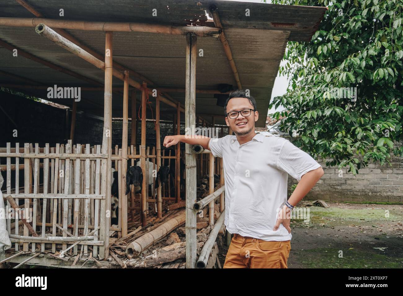 Excited young Asian man standing in front of traditional cage made from ...
