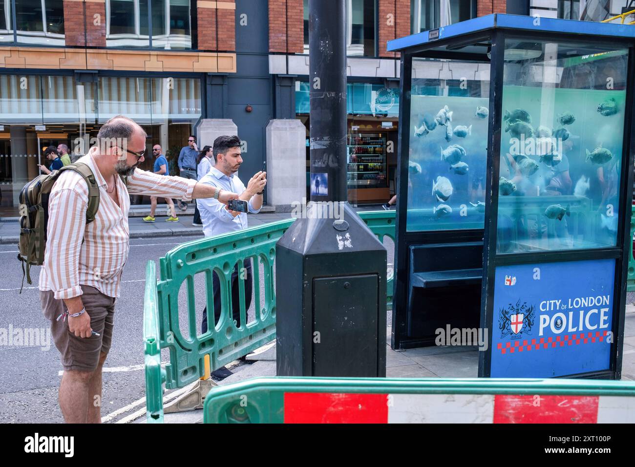 Two men use their mobile phones to take photographs of a piece of art ...