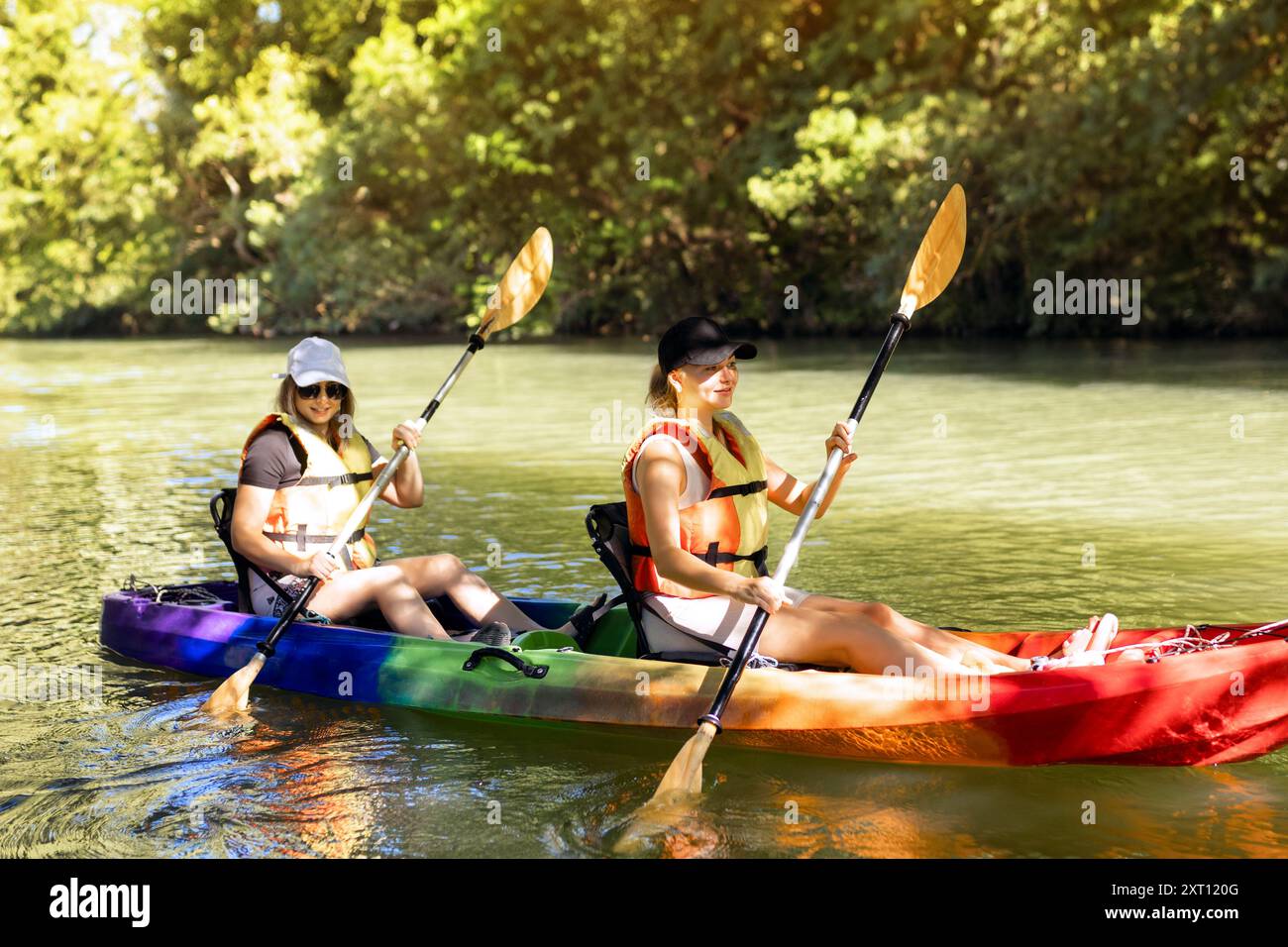 Two young women floating and smiling in a kayak on the river Stock ...