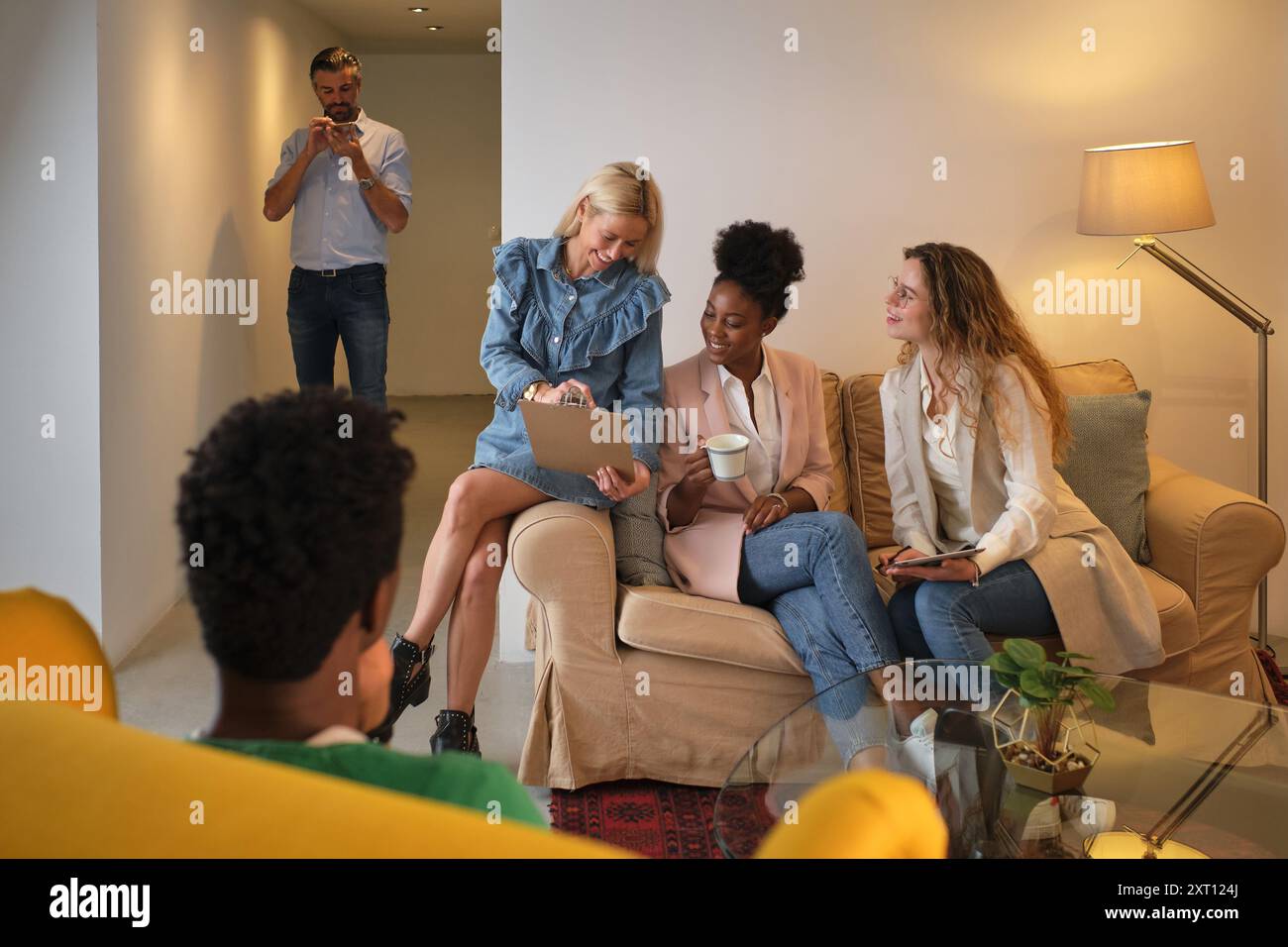 Group of multiracial coworkers sitting in cozy office lounge and having ...