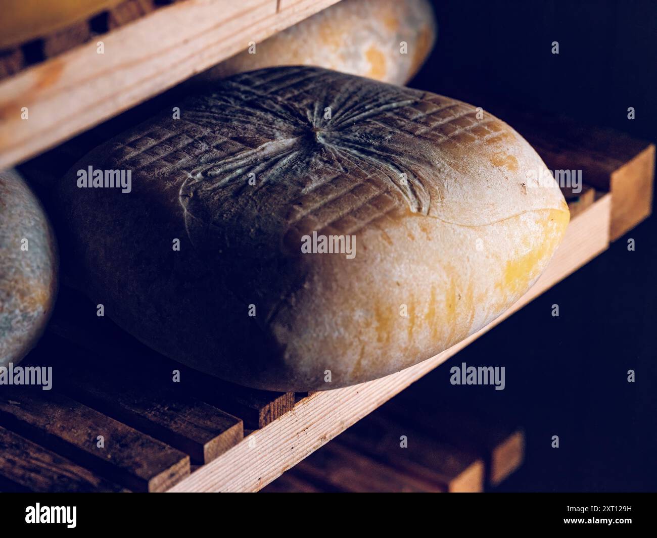 Close-up view of aged Mahon-Menorca cheese resting on wooden shelves ...
