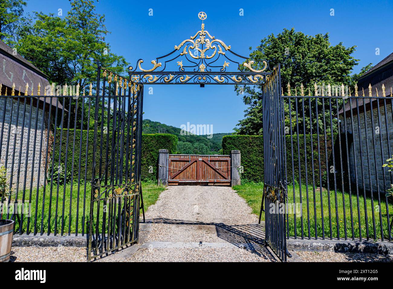 Black wrought iron gate with gold details, gravel path leading to ...