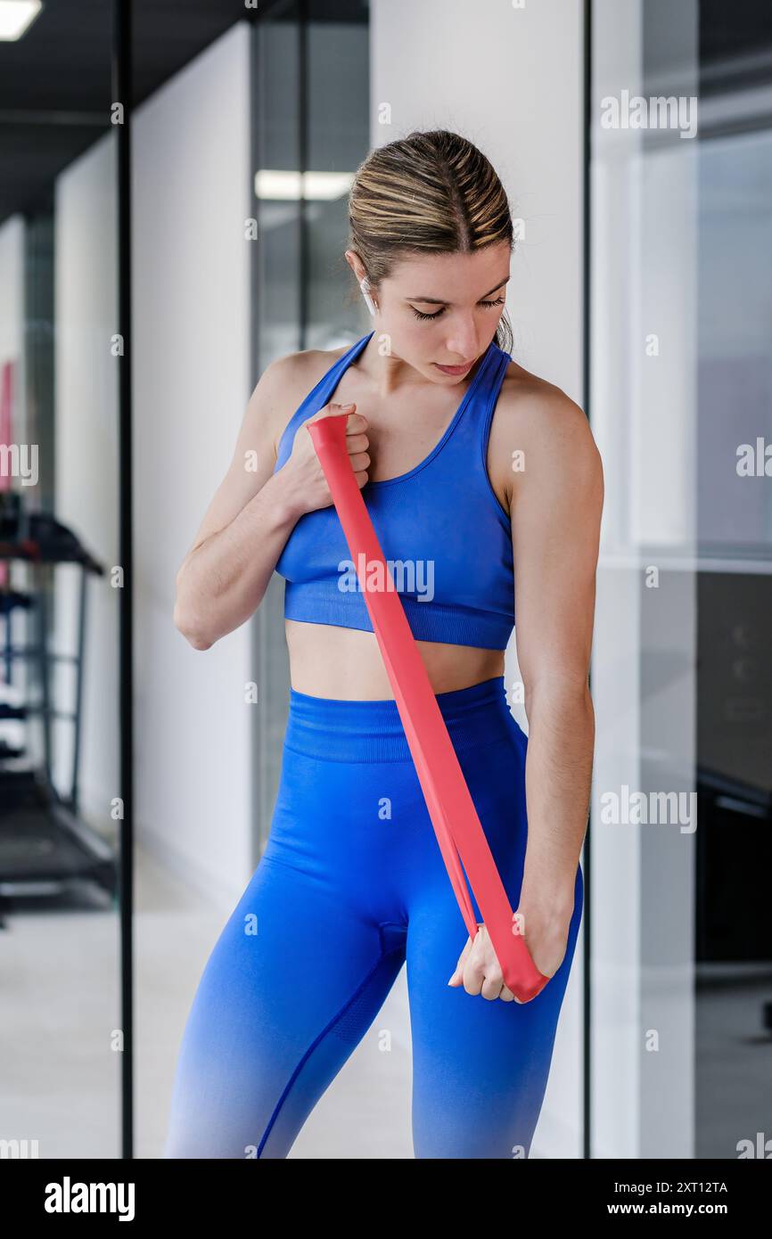 A concentrated woman in a blue workout outfit engages in resistance ...