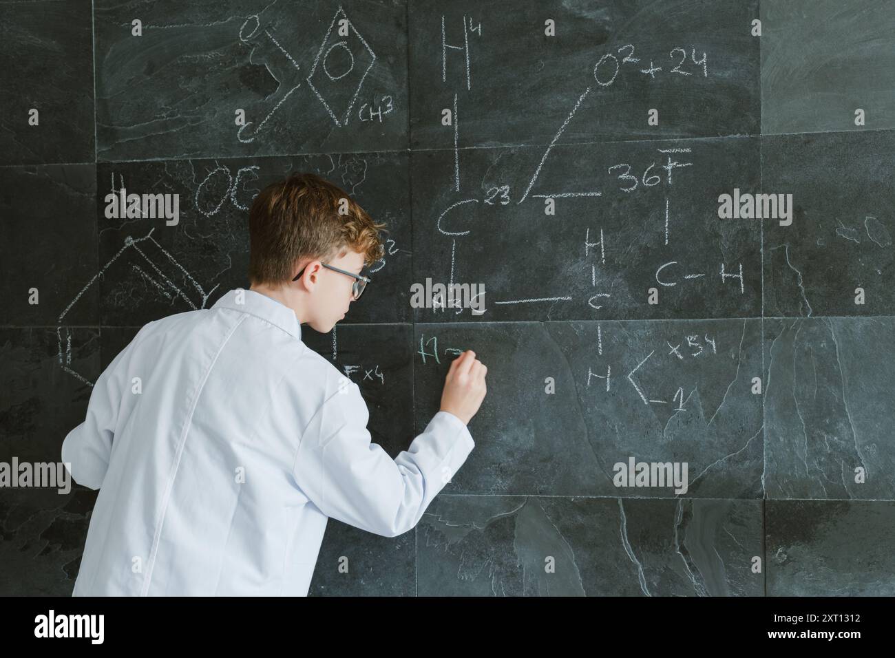 Back view of schoolboy in eyeglasses and white uniform standing while ...