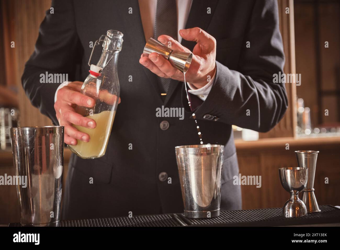 Crop unrecognizable male bartender in black suit pouring alcohol in ...