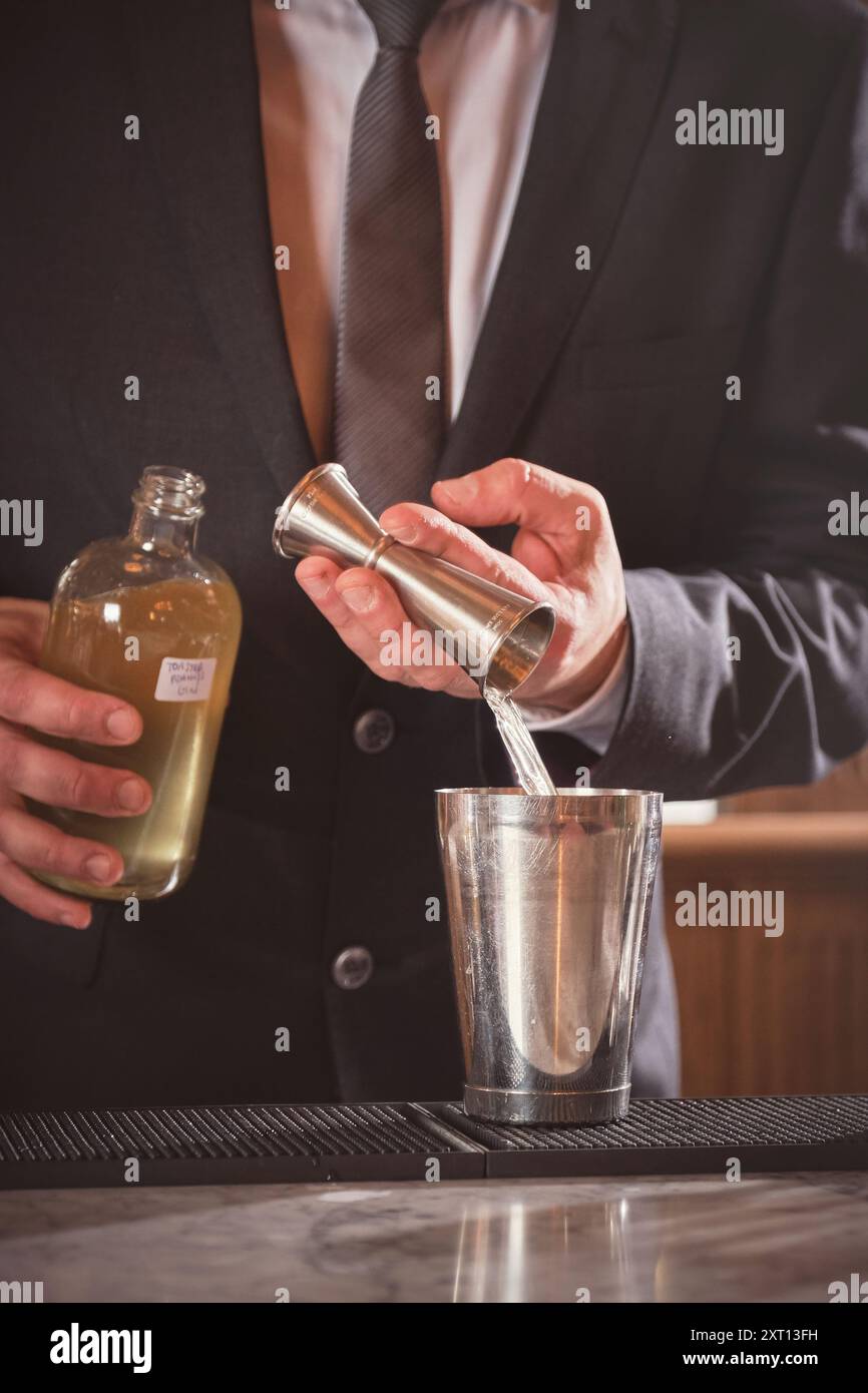 Crop unrecognizable male bartender in black suit pouring alcohol in ...