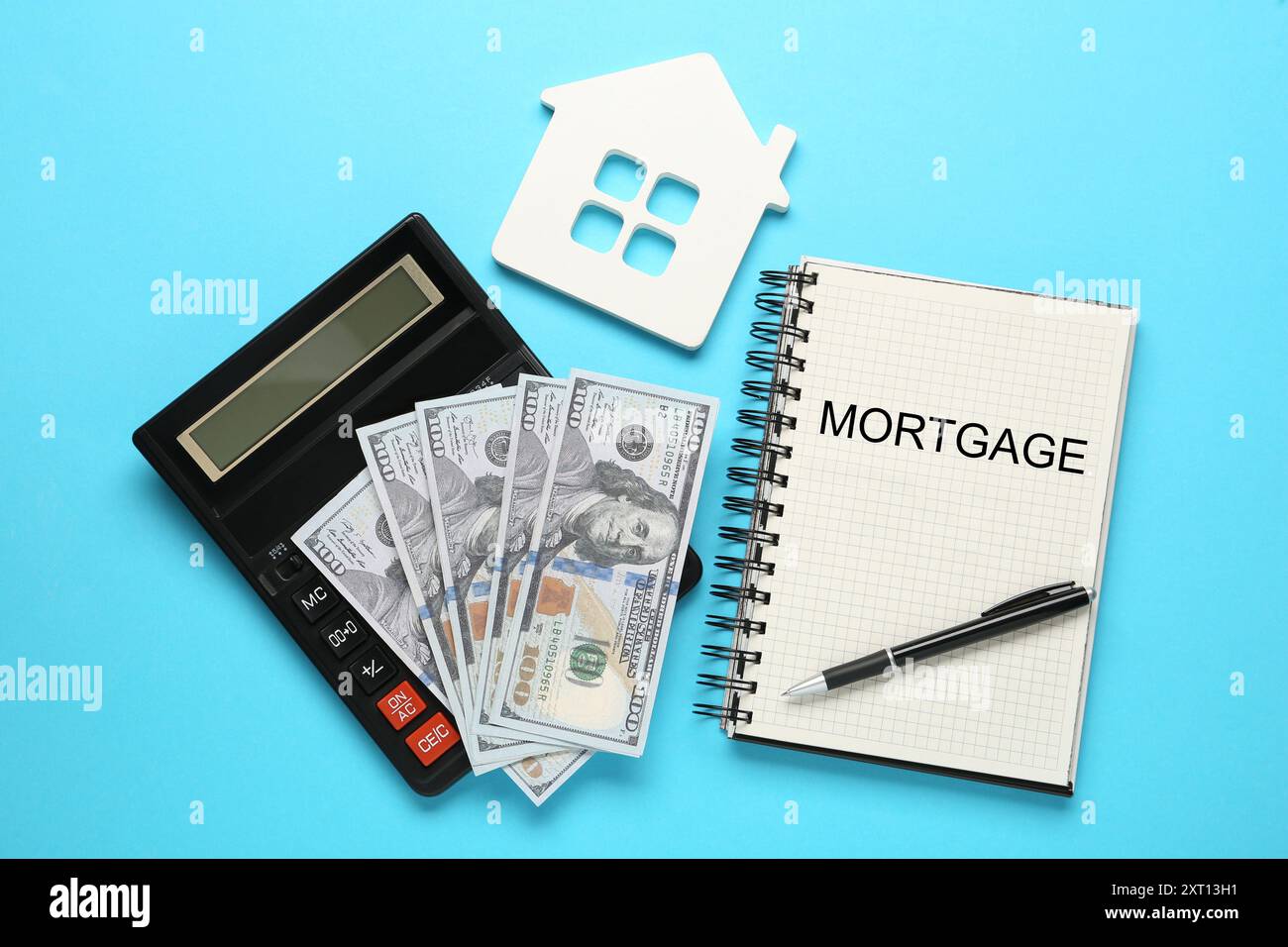 Word Mortgage written in notebook, calculator and dollars on light blue ...