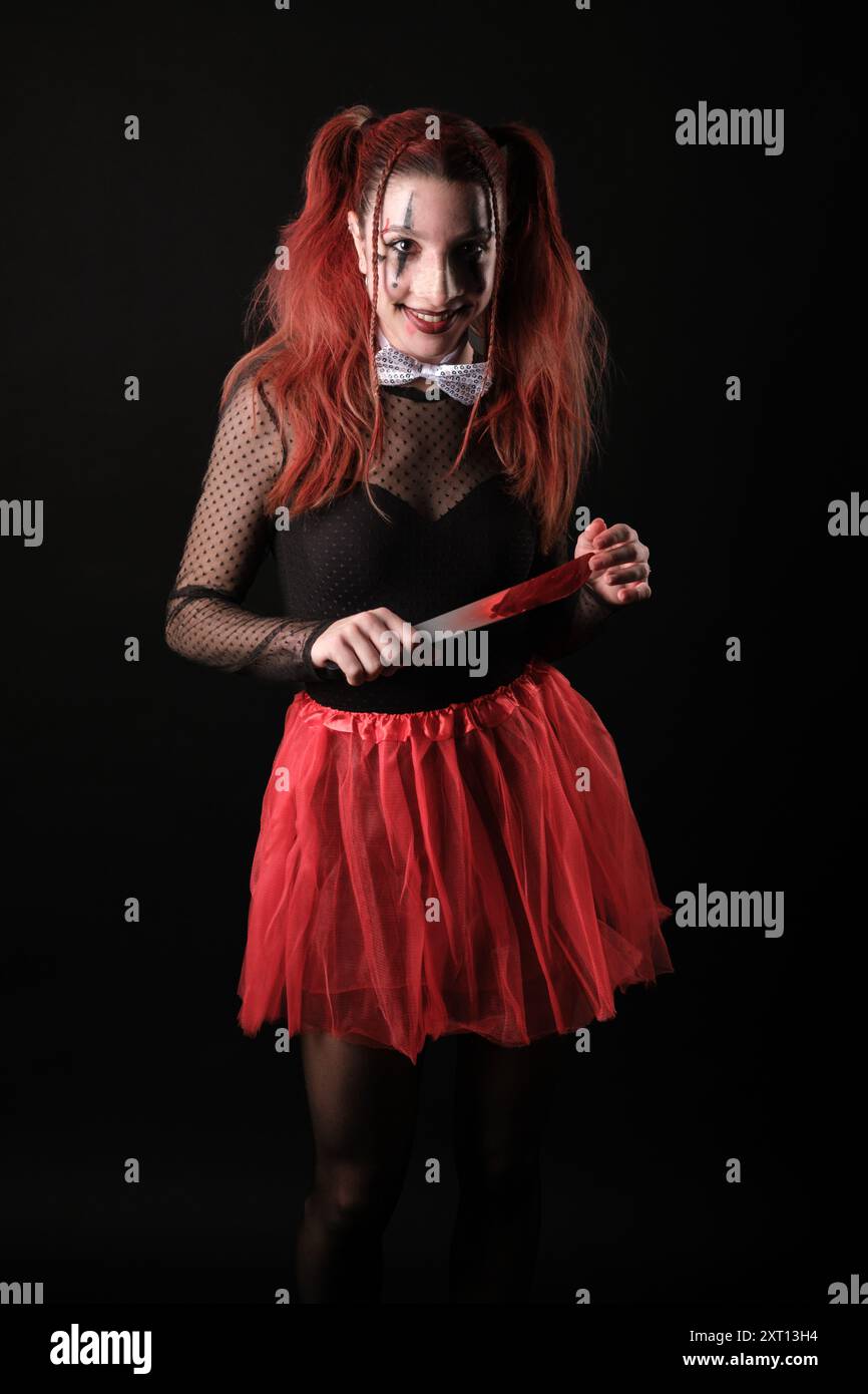 A person in a dark setting holding a knife, wearing a red skirt ...