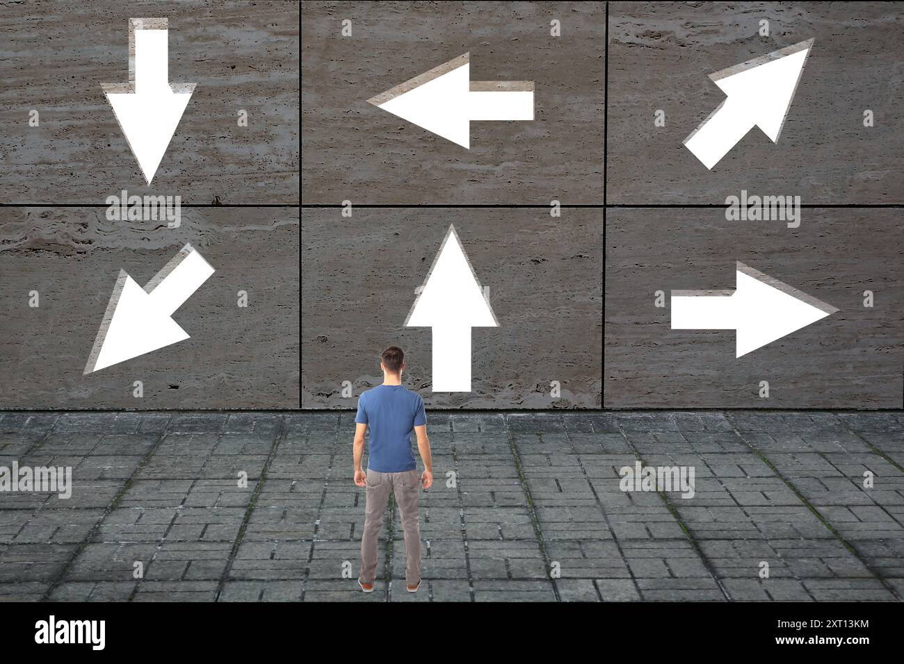 Small man looking at wall with arrows pointing in different directions ...