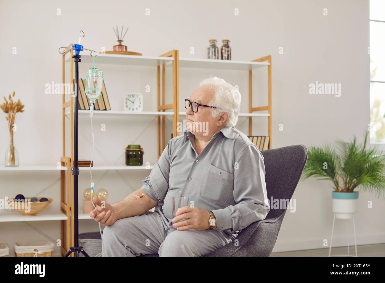 Senior man sitting on chair receiving IV drip infusion and vitamin ...