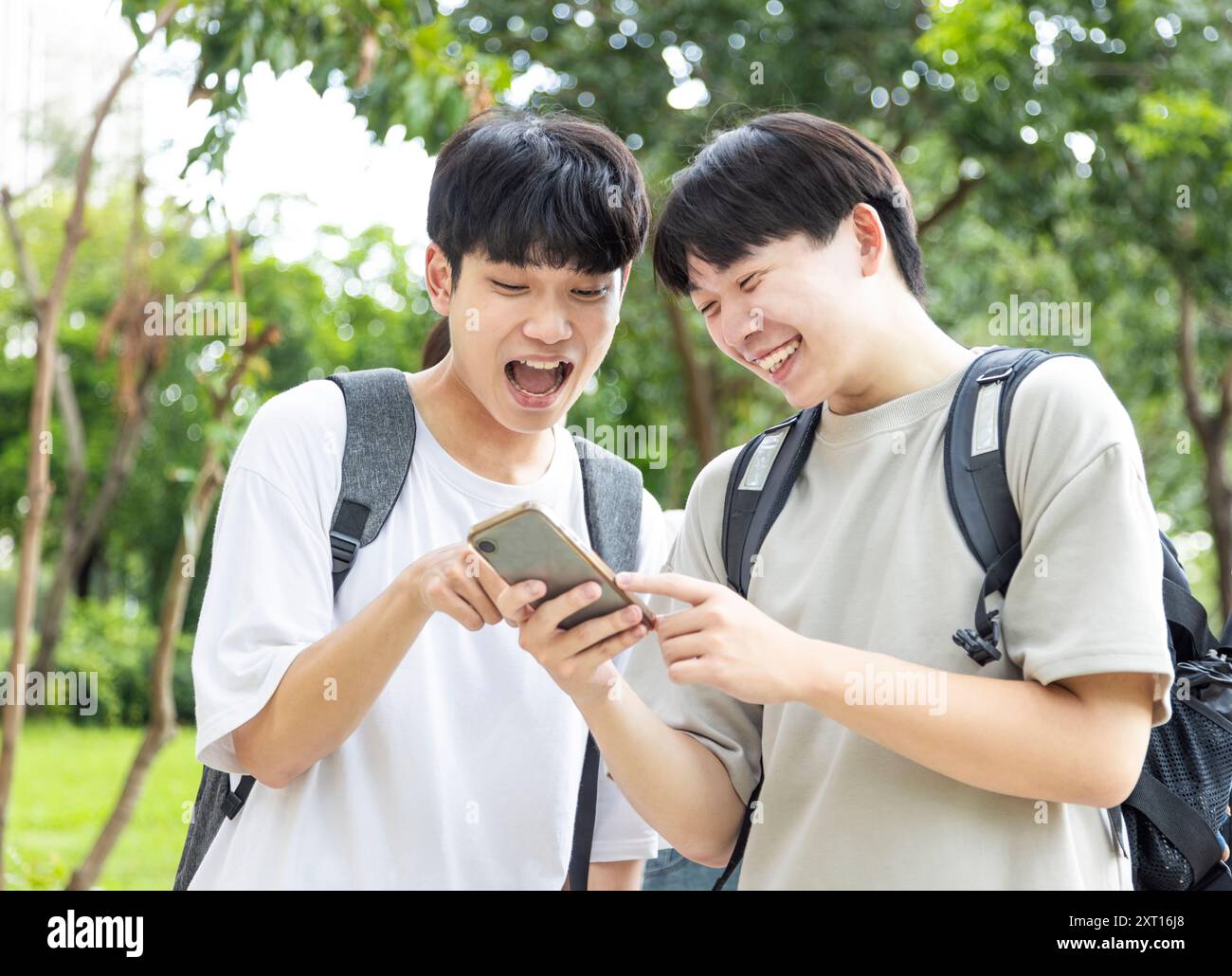 Happy teenagers having fun while using mobile phone in school Stock ...