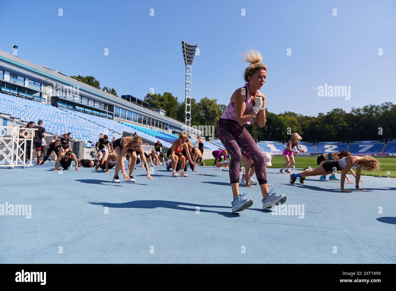 Group of people doing burpees during outdoor work out event. Charity ...