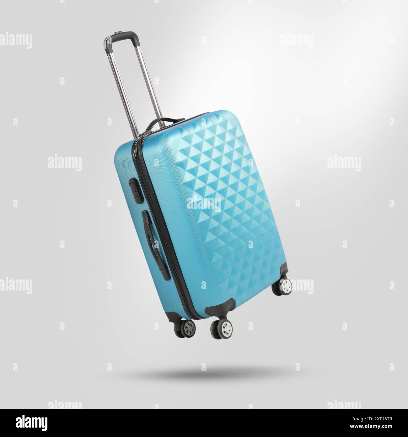 Light blue suitcase in air on light grey background Stock Photo - Alamy