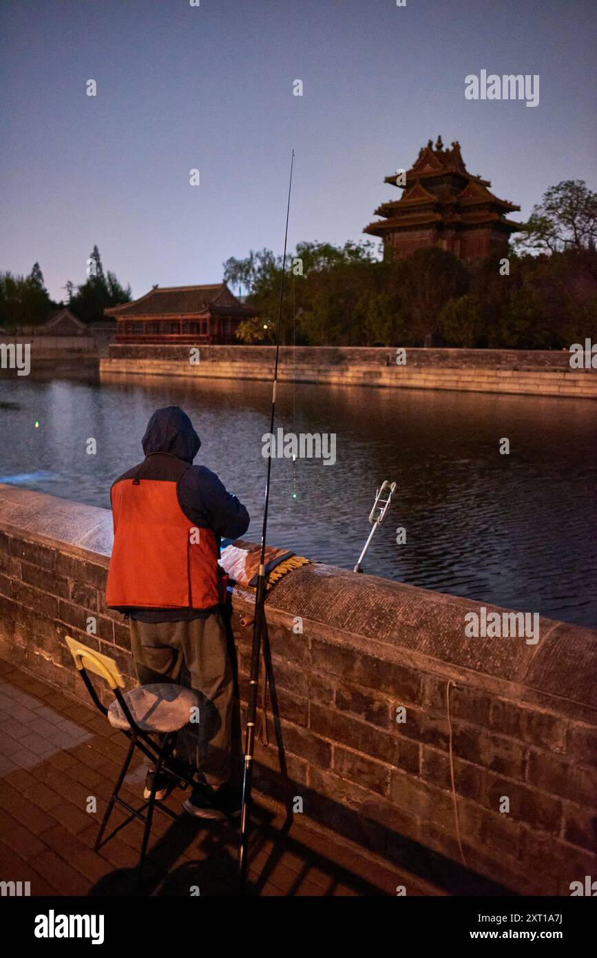 Night fisherman fishing in the water moat surrounding the Forbidden ...
