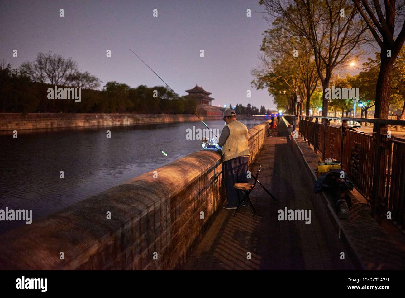 Night fisherman fishing in the water moat surrounding the Forbidden ...