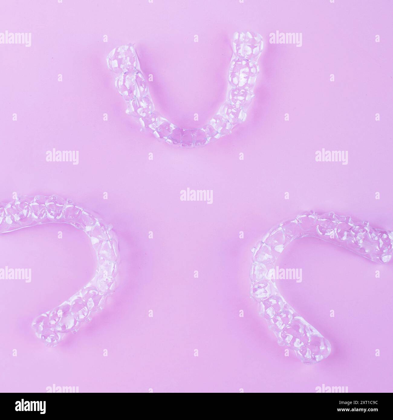 Invisible aligner teeth retainers on a pink background Stock Photo - Alamy